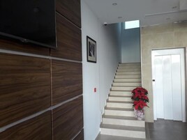 Uma escada com um vaso de planta, um quadro na parede e uma porta no topo.