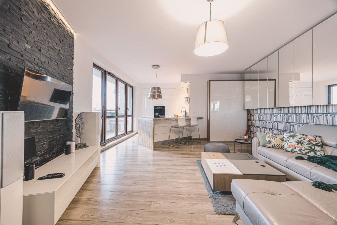 Uma sala de estar moderna com lareira, um sofá, uma mesa de centro e uma área de jantar com cadeiras.