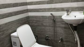 Uma casa de banho com sanita, lavatório e chuveiro.