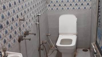 Casa de banho pequena com sanita, lavatório e balde azul.