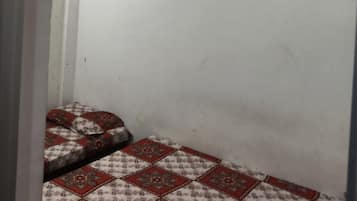 Quarto pequeno e fechado com uma cama e um edredom estampado. Sinal de número visível acima da cama.