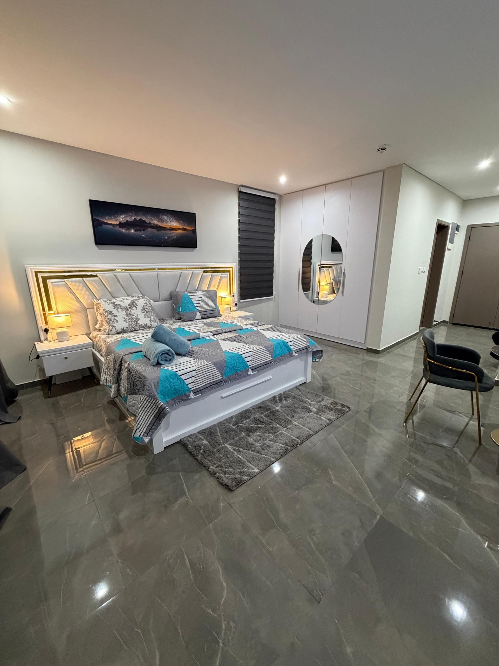 Quarto moderno com cama, mesas de cabeceira, um tapete e espelho fixado na parede.
