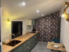 Cozinha moderna com bancada de madeira, pia, janela e parede decorativa com padrão floral.