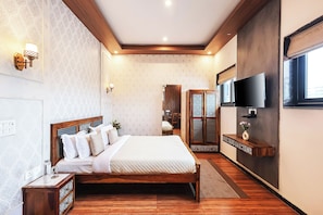 Quarto com cama de madeira, mesas de cabeceira, televisão e papel de parede estampado.