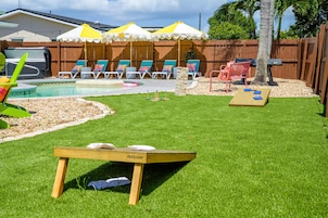 Um quintal com piscina, espreguiçadeiras e deck de madeira.