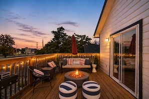 Um deck com móveis de exterior, lareira e luzes de corda.