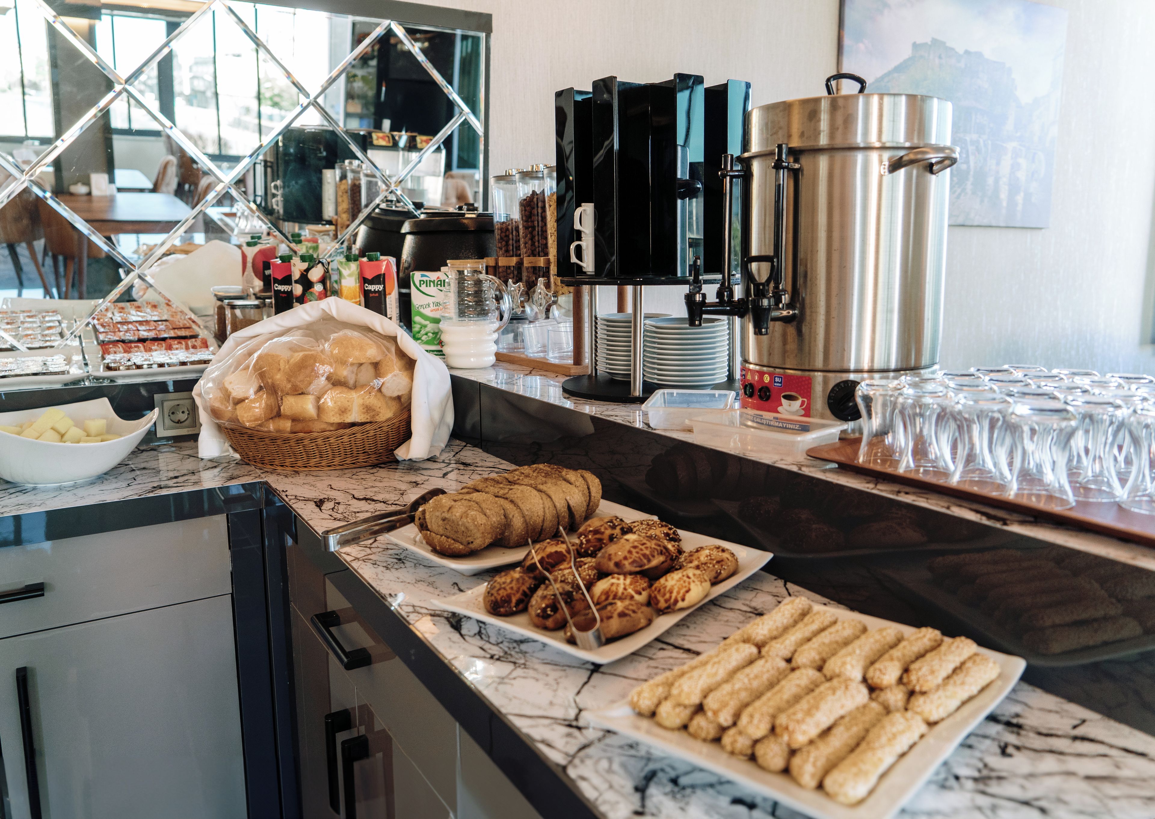 Buffet de café da manhã com diversos pães, bolos e uma estação de café.