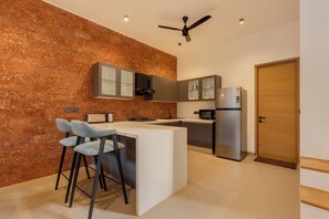Uma cozinha moderna com ilha central, banquetas, eletrodomésticos de aço inoxidável e backsplash em tom de cobre.