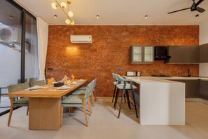 Cozinha moderna com ilha central, área de jantar com mesa comprida e cadeiras, e forno embutido.