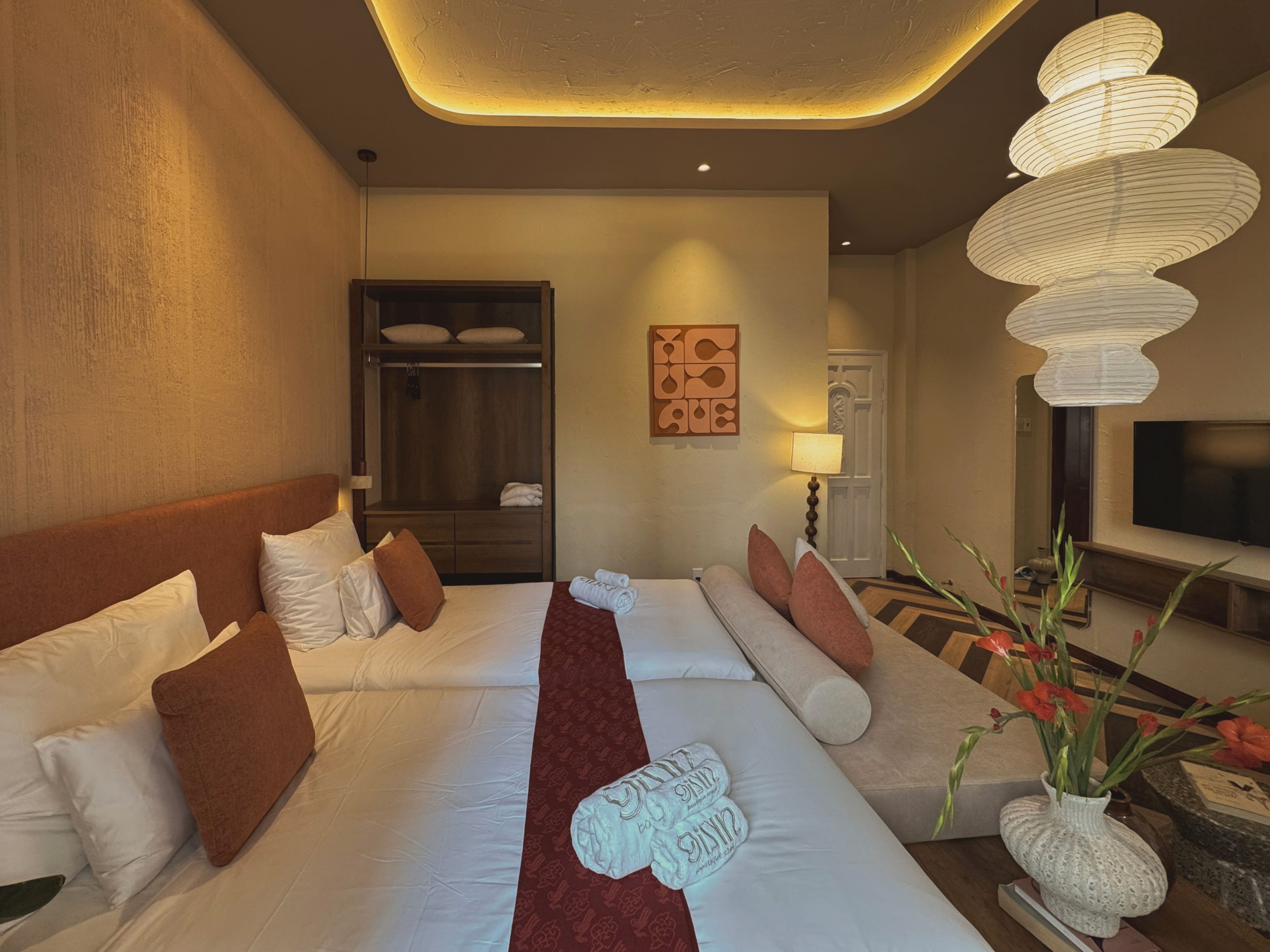Quarto de hotel com cama grande, sofá, televisão e armário.