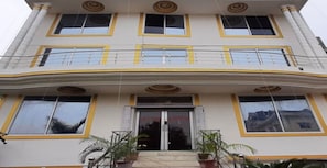 Um edifício com vários andares, varanda curva, janelas amplas e entrada central.