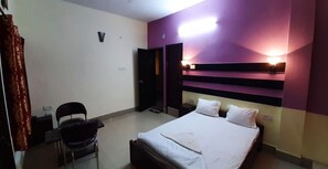 Quarto de hotel com cama, poltrona, escrivaninha e porta.