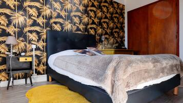 Quarto com uma cama grande, mesa de cabeceira, abajur e guarda-roupa.