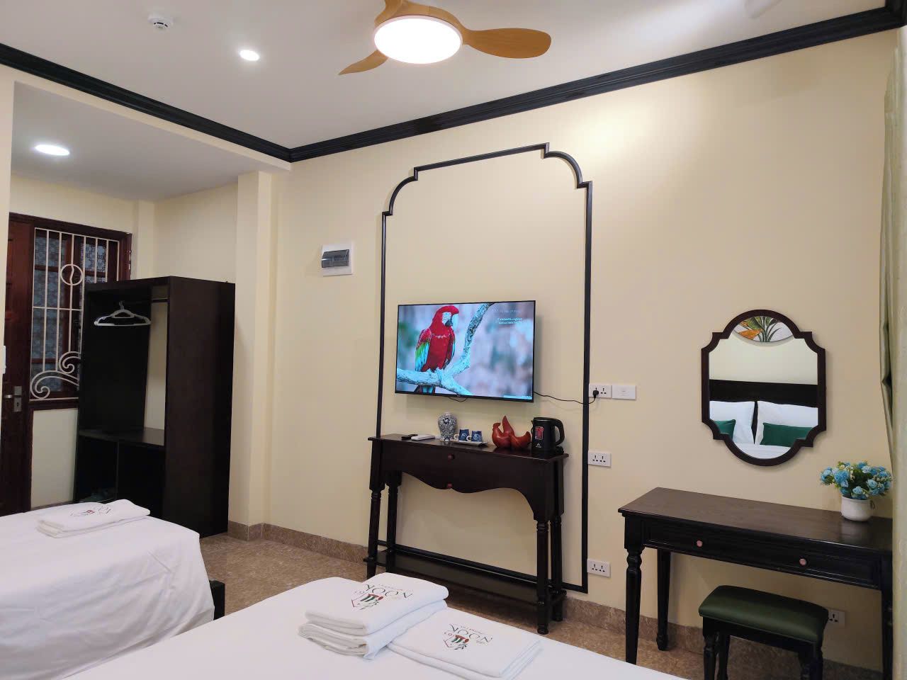 Quarto de hotel com duas camas, televisão, espelho e escrivaninha com cadeira.