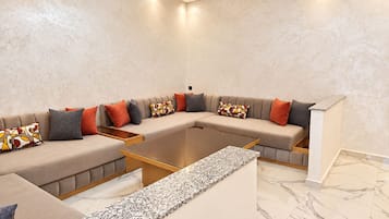 Uma sala de estar moderna com um sofá seccional, uma mesa de centro e piso de mármore.