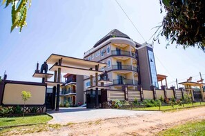 Edifício residencial com várias andares, fachada curva, sacadas e entrada com portão.