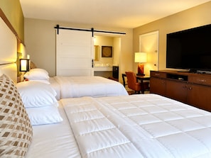 Quarto de hotel com duas camas, uma escrivaninha, televisão e guarda-roupa.