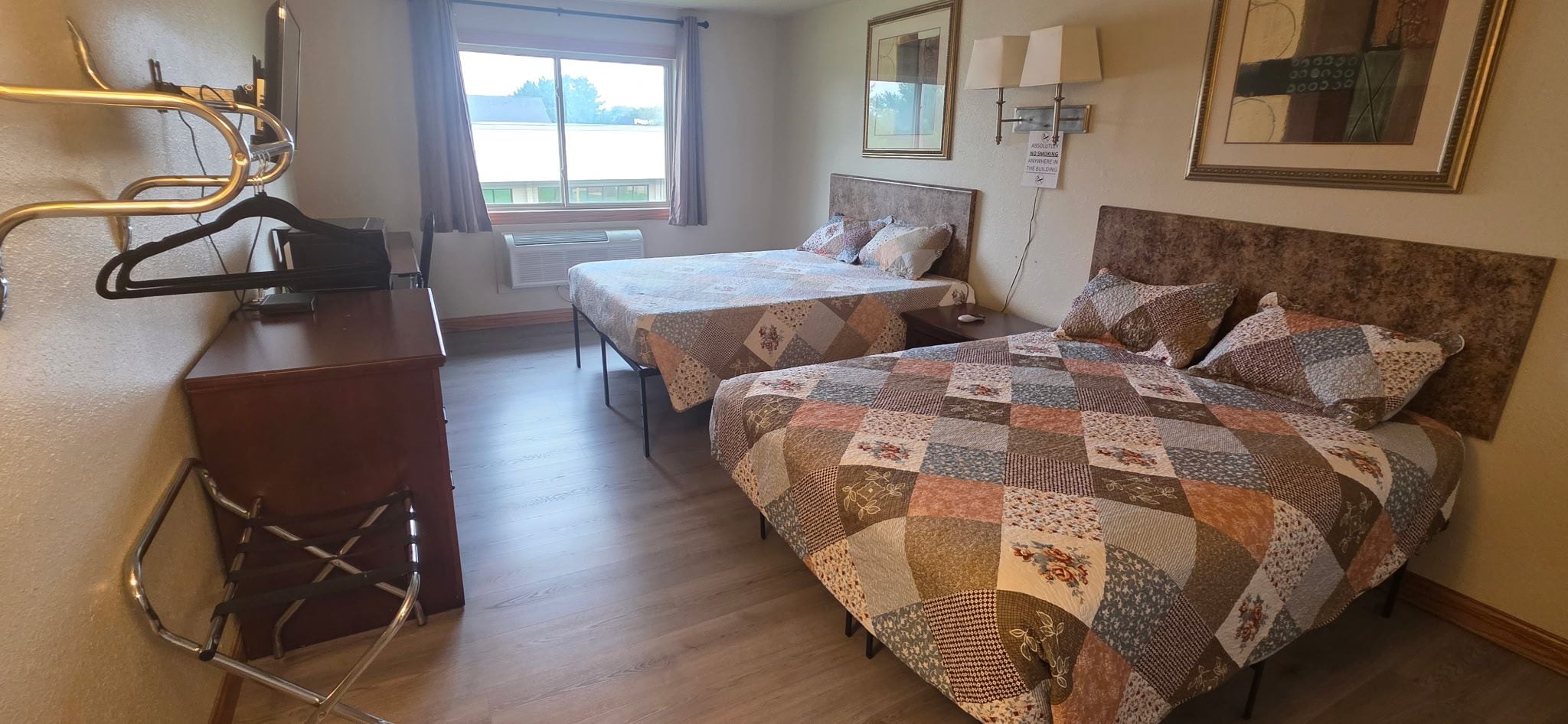 Quarto de hotel com duas camas, uma mesa e uma cadeira.