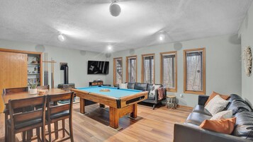 Quarto com mesa de bilhar, sofá e televisão.