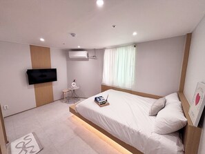 Quarto moderno com cama, mesa de cabeceira e televisão de tela plana fixada na parede.