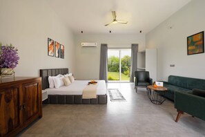 Quarto de hotel moderno com cama, sofá verde, armário de madeira e vista para o exterior.