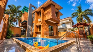 Um edifício moderno com piscina, área de estar ao ar livre e palmeiras.
