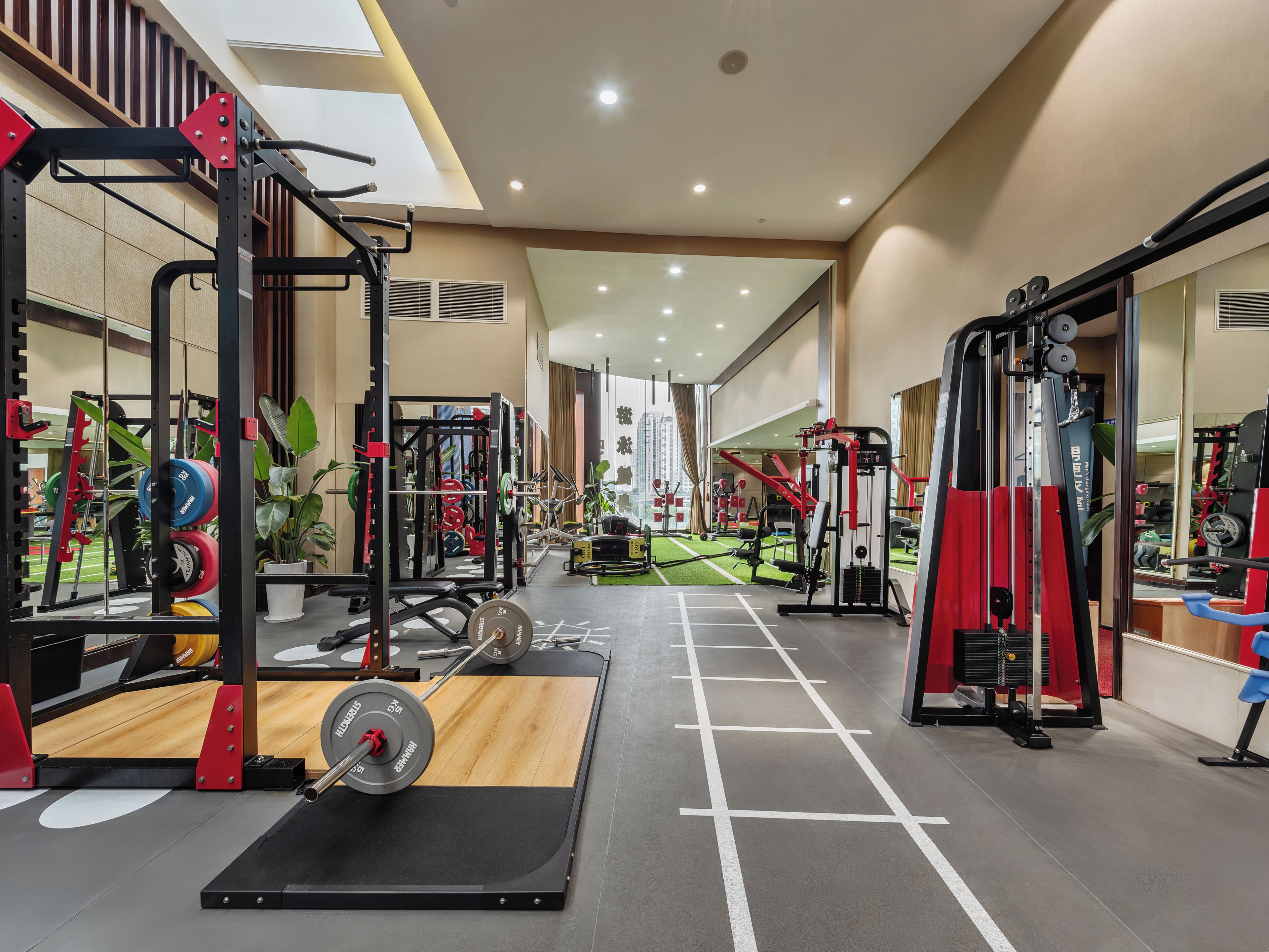 Academia com diversos equipamentos de exercício, um espelho grande e vista para a cidade.