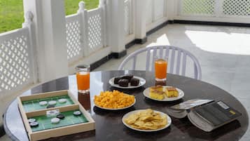 Uma mesa posta com petiscos, bebidas e um jogo de tabuleiro em uma área externa coberta.