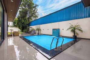 Piscina com água azul cristalina, cercada por um deck revestido com azulejos.