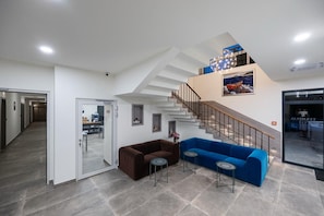 Um interior moderno com uma escada, um sofá azul e um sofá castanho.
