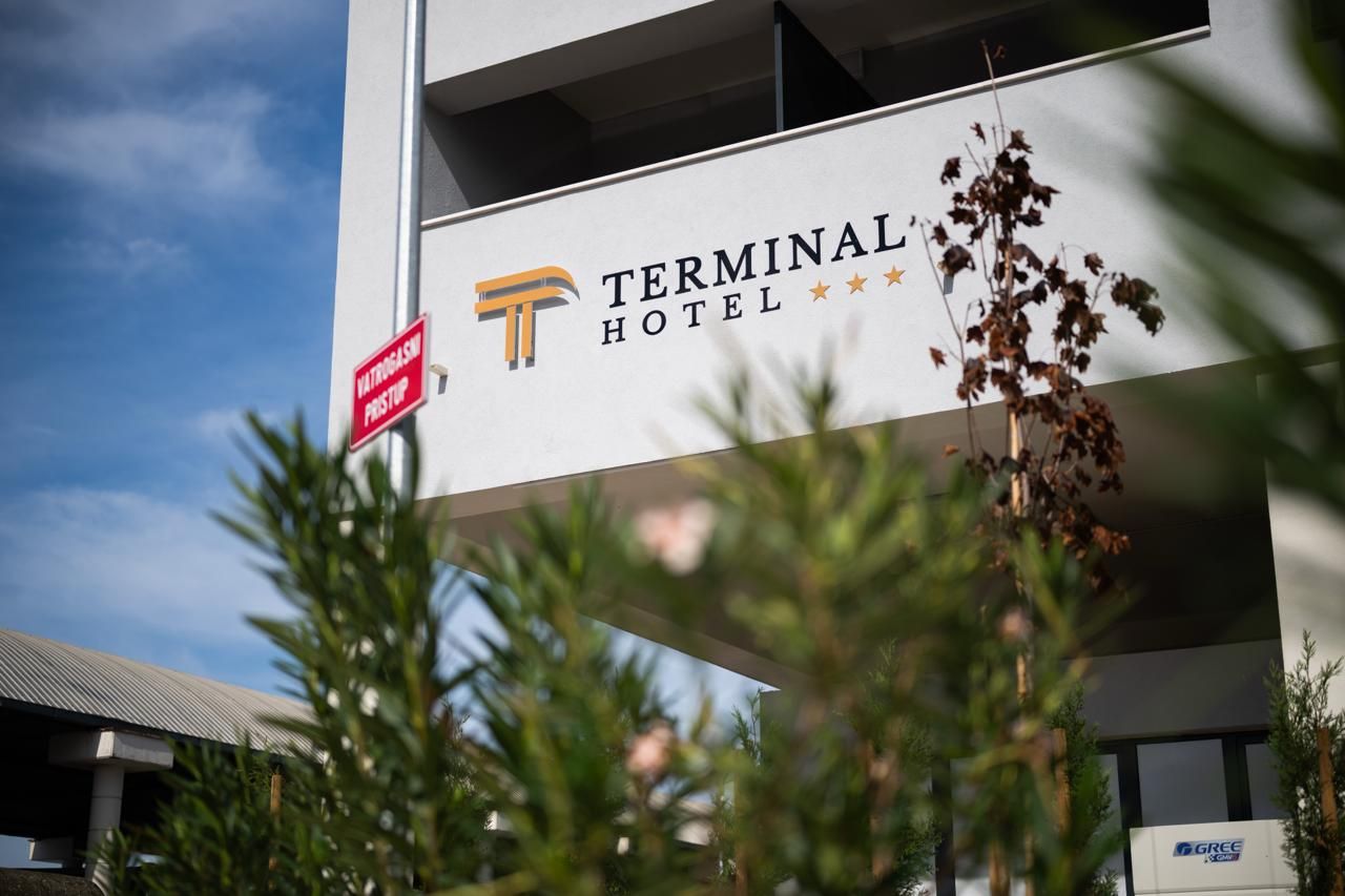 Um edifício com uma placa indicando 'Terminal Hotel' e uma placa vermelha com 'Inscrição no IVA'.