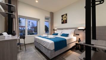 Quarto de hotel moderno com uma cama grande, uma escrivaninha e uma janela com vista para edifícios.