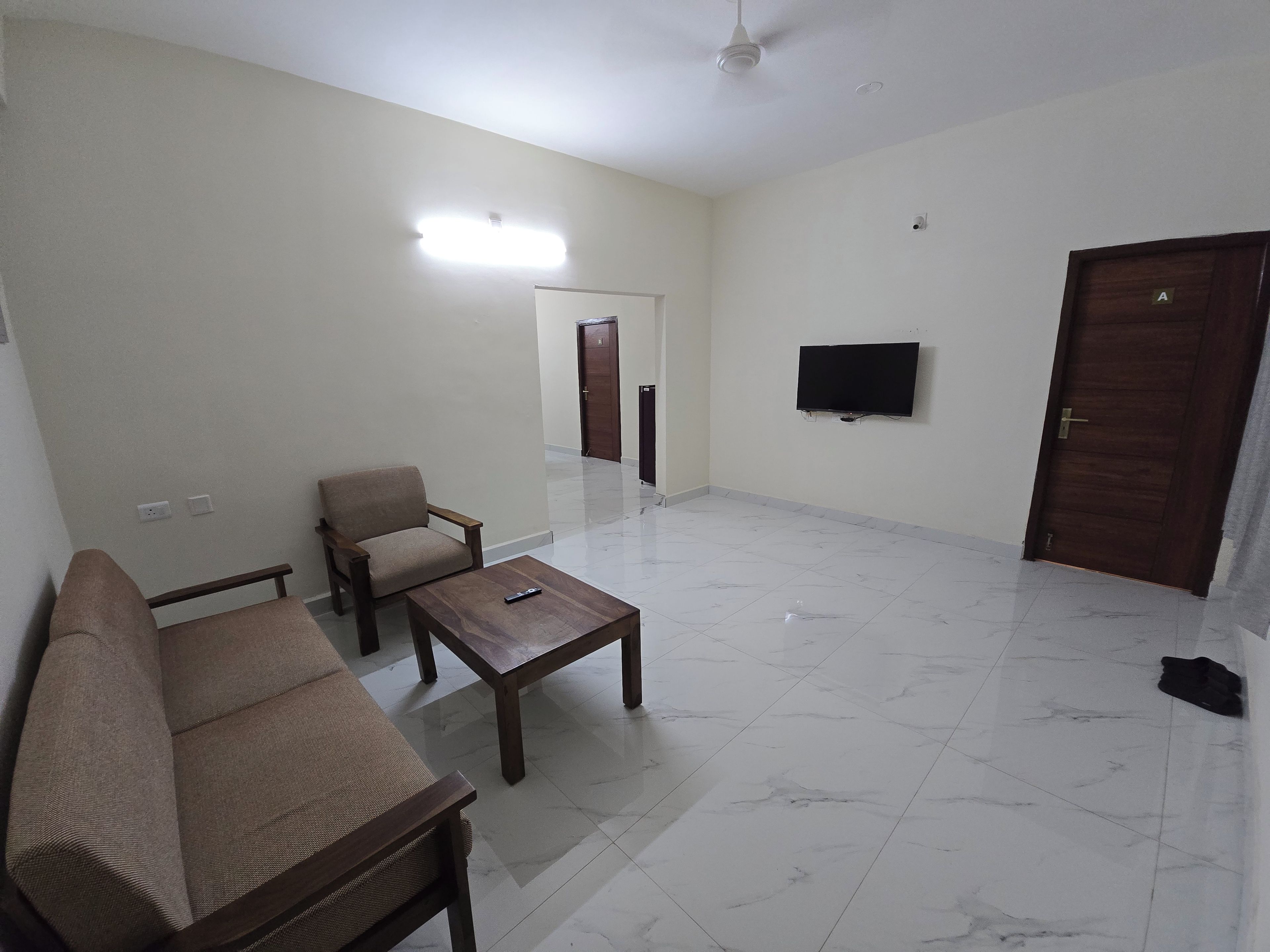 Uma sala de estar com sofá, poltrona, mesa de centro e uma televisão de tela plana na parede.