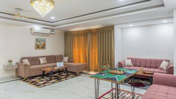 Uma sala de estar moderna com sofá, mesa de centro, lustre e uma janela grande com cortinas.