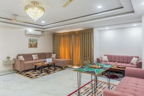 Uma sala de estar moderna com sofá, mesa de centro, lustre e uma janela grande com cortinas.