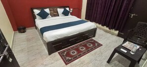 Quarto com cama, mesa de cabeceira, cadeira, parede vermelha e uma porta.