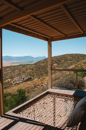 Uma área de estar coberta ao ar livre, com vista para uma paisagem montanhosa.