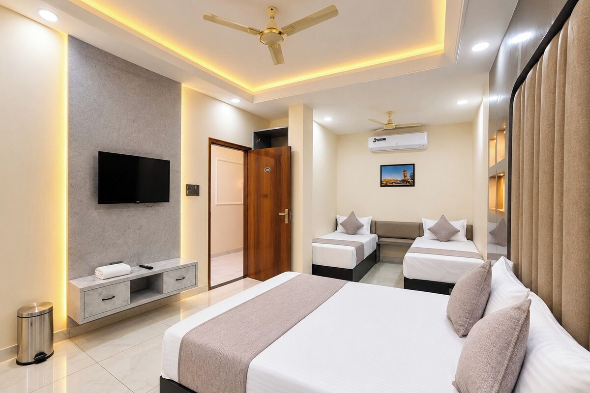 Quarto de hotel com cama grande, televisão, escrivaninha e ventoinha no teto.