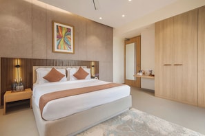 Quarto moderno com uma cama grande, mesa de cabeceira com abajur, guarda-roupa e uma obra de arte pendurada na parede.