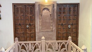 Conjunto de portas de madeira ornamentadas com esculturas detalhadas, uma porta central com arco decorativo e um guarda-corpo decorativo na frente.