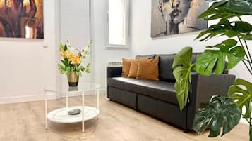 Uma sala de estar moderna com um sofá de couro, uma mesa de centro de vidro e plantas verdes grandes.
