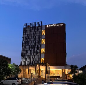 Hotel com fachada moderna, entrada visível e escadaria que leva ao saguão.