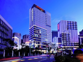 Um hotel moderno com muitos andares, letreiros iluminados e um projeto arquitetônico arrojado, com uma rua movimentada e rastros de luz.