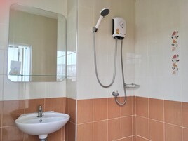 Casa de banho com lavatório branco, chuveiro manual e aquecedor de parede.