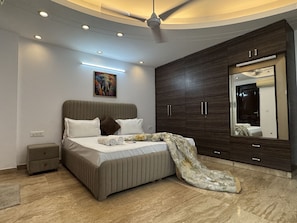 Quarto moderno com cama, mesas de cabeceira, guarda-roupa e ventoinha de teto.