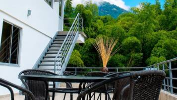 Terraço com mobiliário externo, escadaria e vista para uma montanha e floresta.