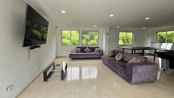 Uma sala de estar moderna com televisão de tela plana, dois sofás, uma mesa de centro e uma mesa de pingue-pongue.