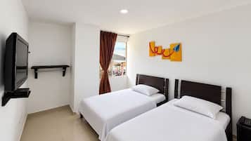 Quarto de hotel com duas camas, televisão, janela com cortinas e obras de arte na parede.