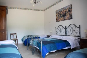 Quarto com duas camas, uma cadeira, um quadro na parede e uma porta de madeira.