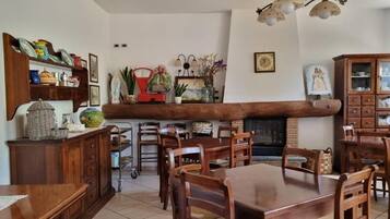 Uma sala de jantar com mesa e cadeiras de madeira, lareira e um armário com louças.